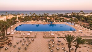 Um resort com uma piscina grande, espreguiçadeiras e palmeiras.