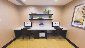 Uma sala de conferências com duas mesas, cadeiras, uma estante com objetos decorativos e um quadro na parede.