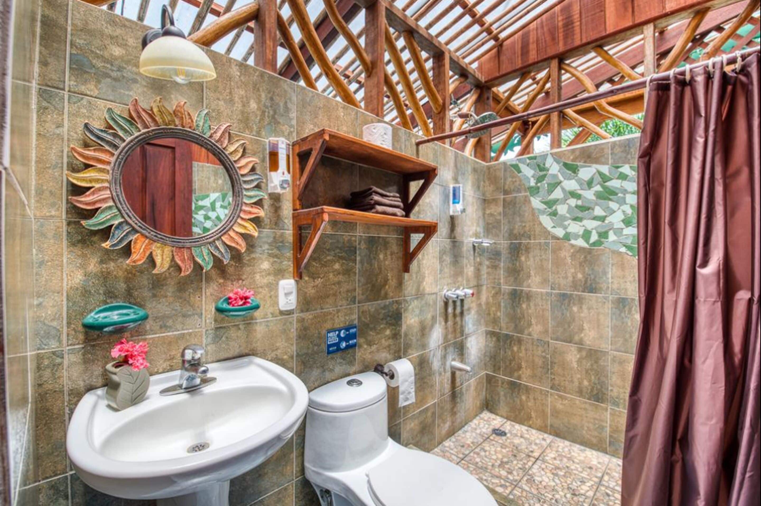 Casa de banho com prateleira de madeira, espelho, lavatório e sanita.