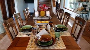 Uma mesa de jantar posta com pratos, tigelas e hashis verdes, com uma peça central de abacaxi e velas.