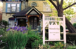 Um edifício com uma placa que diz "Manderley Bed & Breakfast Inn" e um aviso informando que "Reservas são obrigatórias".