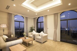 Uma sala de estar espaçosa com teto alto, janelas arqueadas grandes e vista para a paisagem urbana.