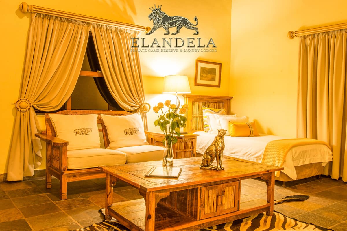 Quarto com sofá, cama, mesa de centro de madeira e luminária.