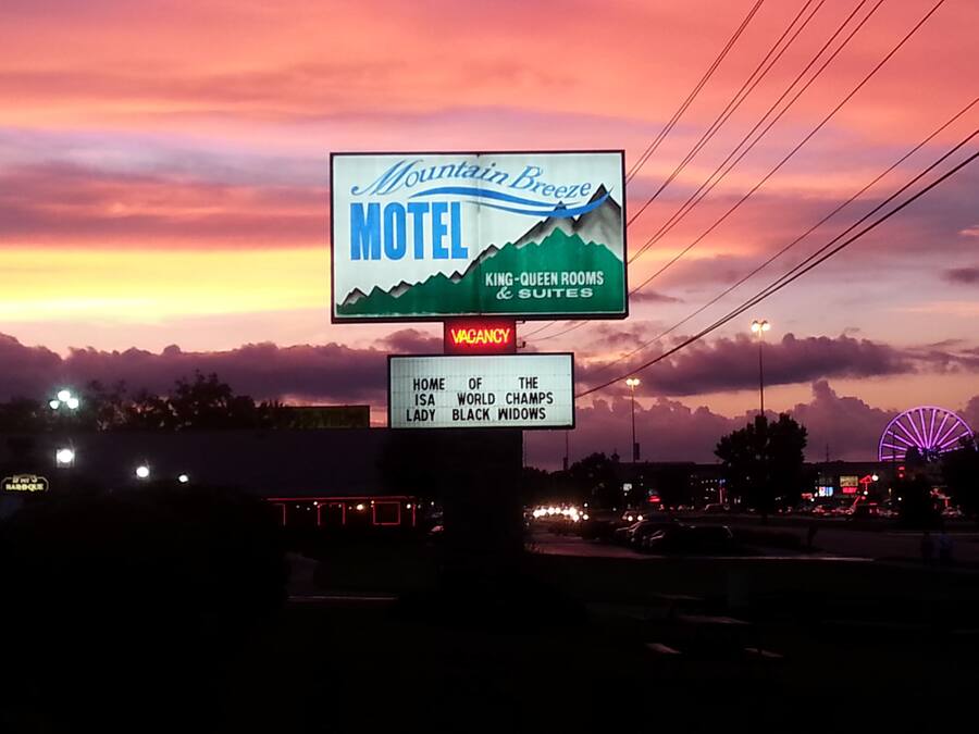 Placa de motel com montanhas e céu ao fundo, indicando um local pitoresco.