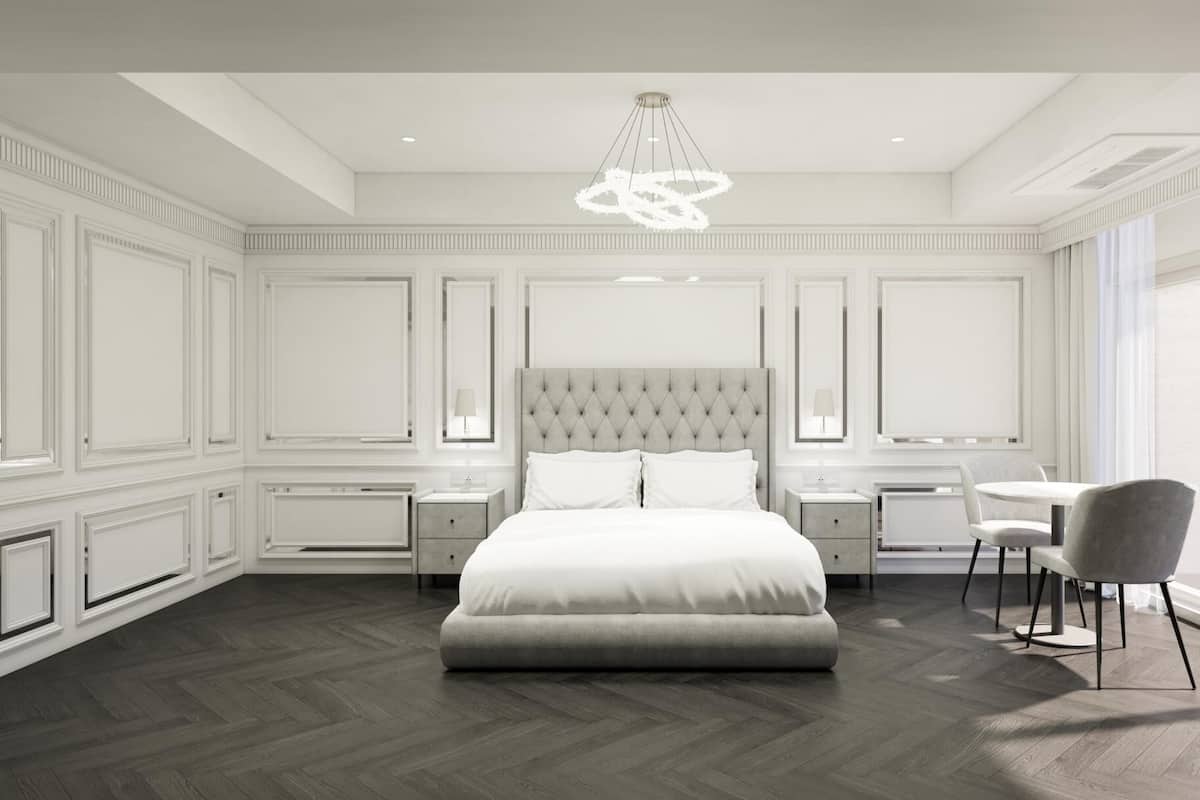Um quarto moderno com uma cama grande, mesas de cabeceira, uma cadeira e um candelabro.