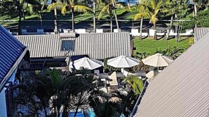 Um resort com área de piscina, palmeiras e vista para o oceano.