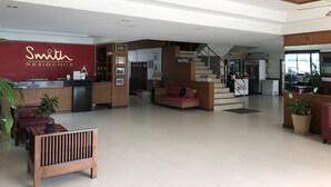 Um hall amplo com balcão de recepção, escada e áreas de estar.