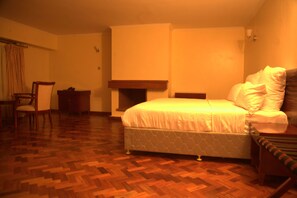 Quarto com cama, cadeira, mesa de cabeceira e lareira.