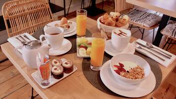 Mesa de café da manhã com pratos de comida, copos de bebidas e diversos acompanhamentos.
