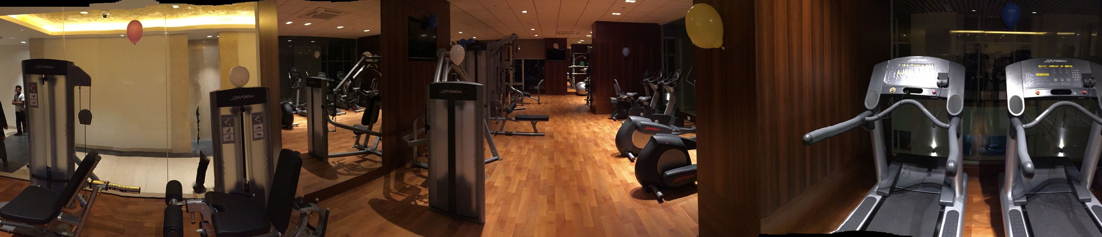 Uma academia com diversos equipamentos de exercício, incluindo esteiras e máquinas de musculação.