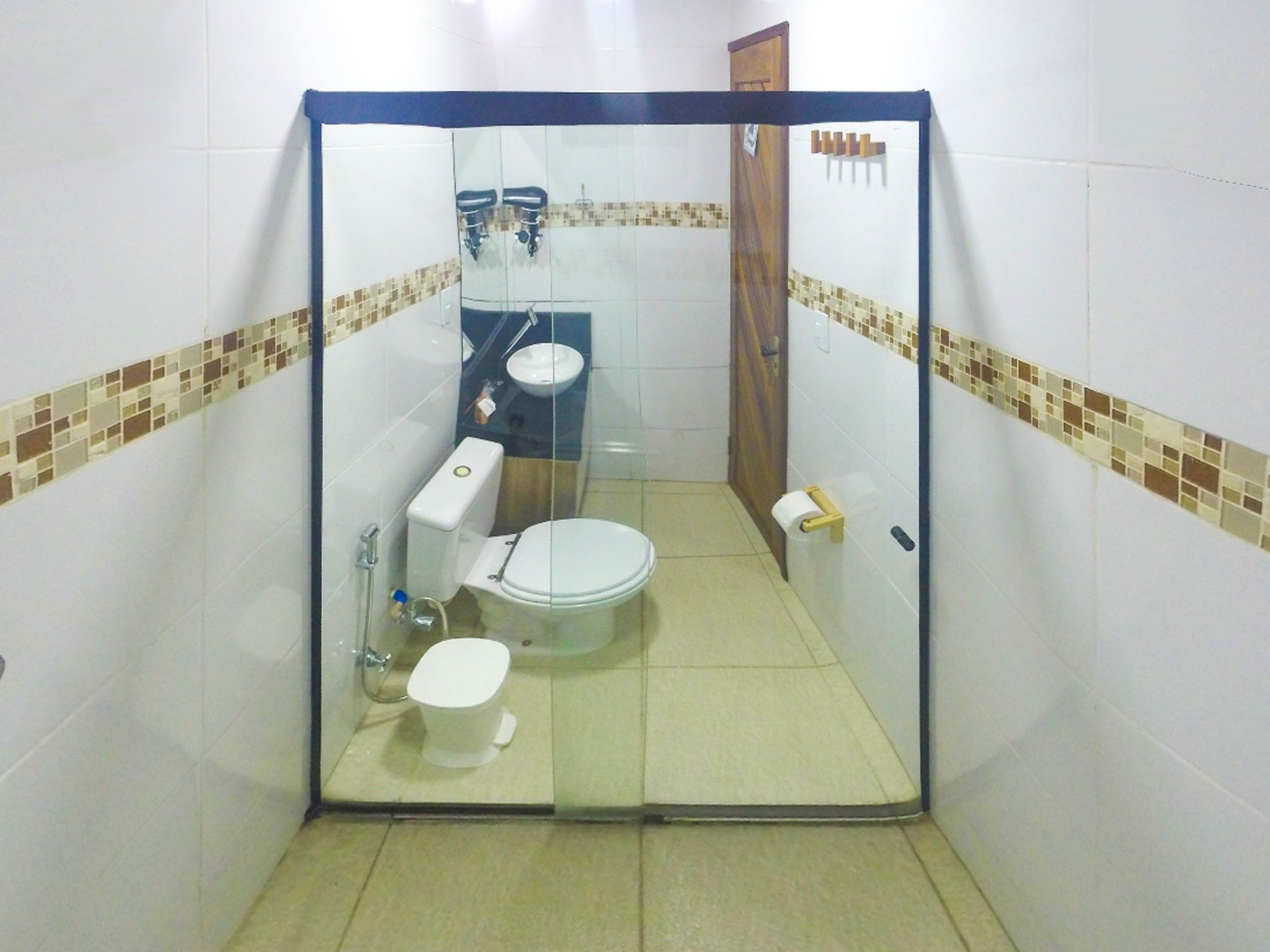 Casa de banho pequena e fechada, com sanita, lavatório e chuveiro.