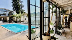 Uma casa moderna com piscina, janelas amplas e plantas em vasos.