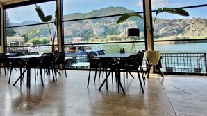 Uma sala de jantar com grandes janelas de frente para um lago e montanhas.
