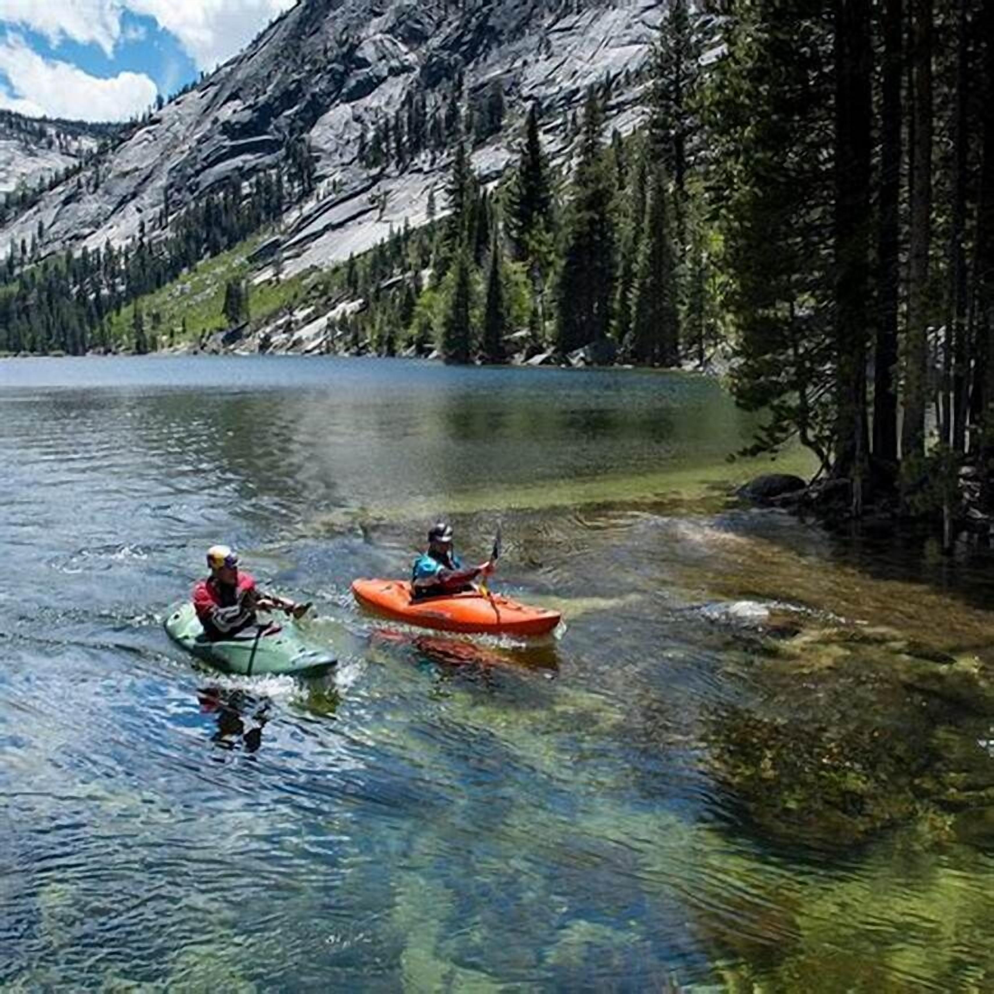 Dois praticantes de caiaque em um lago calmo, rodeados por montanhas arborizadas.