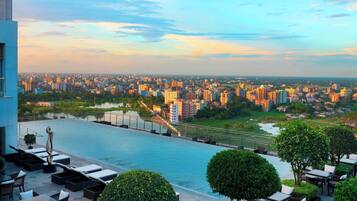 Piscina no terraço com espreguiçadeiras e vista para a paisagem urbana.