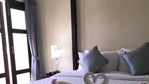 Quarto de hotel com cama decorada com arranjo de toalha em forma de cisne e uma flor.