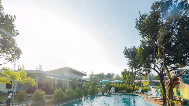 Piscina com água azul cristalina, rodeada por árvores e espreguiçadeiras.