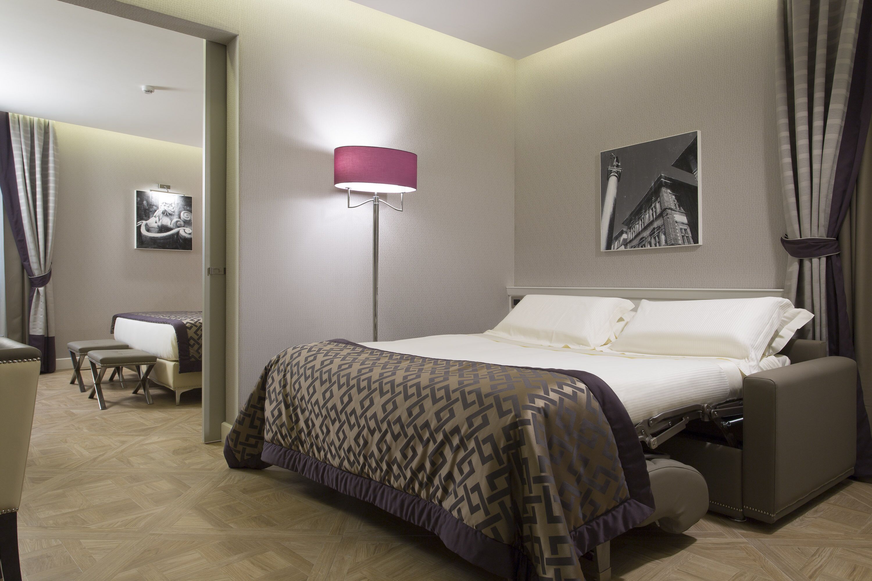 Quarto de hotel com cama, escrivaninha, cadeira e abajur.