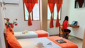 Quarto de hotel com duas camas, uma escrivaninha e uma cadeira.