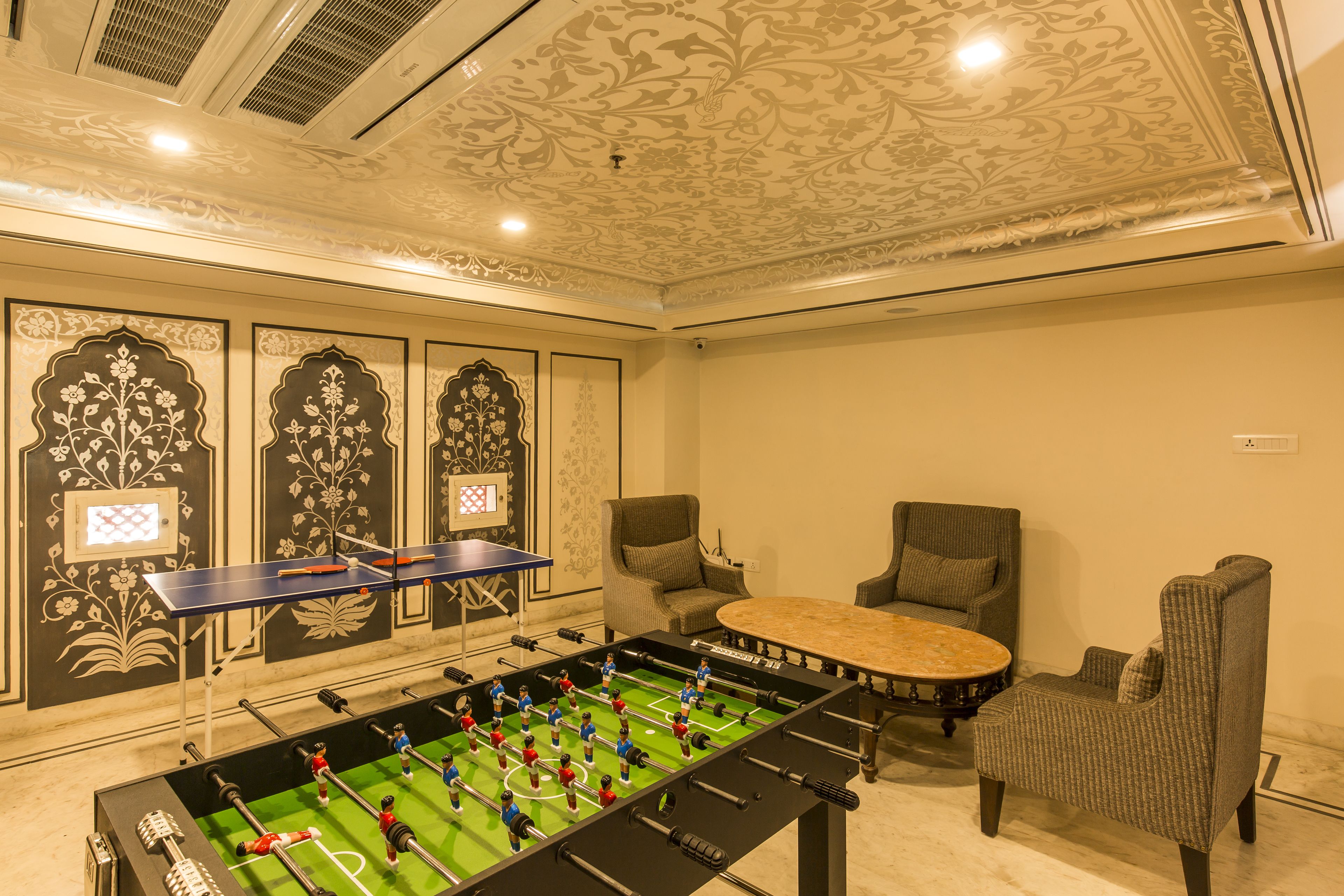 Um quarto com uma mesa de futebol, uma mesa de tênis de mesa e duas poltronas.
