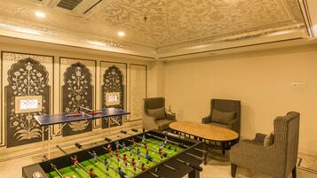 Um quarto com uma mesa de futebol, uma mesa de tênis de mesa e duas poltronas.