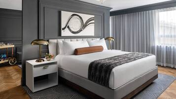 Quarto moderno com uma cama grande, uma mesinha de cabeceira, um abajur decorativo e uma obra de arte na parede.