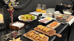 Um buffet de café da manhã com diversos alimentos, incluindo frutas, doces e bebidas.