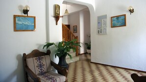 Um corredor com um banco de madeira, um vaso de planta e quadros nas paredes.