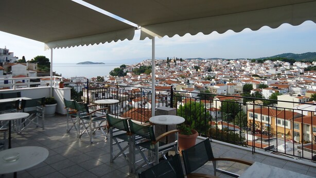 Um terraço com área de estar ao ar livre, vista para uma vila costeira e céu claro.