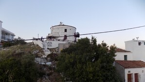 Um edifício branco com uma torre redonda, cercado por árvores e uma escadaria que leva até ele.