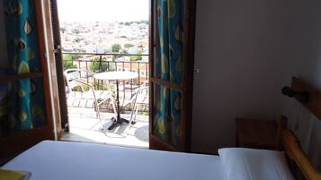Varanda com mesa e cadeiras, uma cama e vista para a paisagem urbana.
