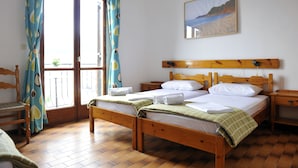 Quarto com cama de madeira, mesa de cabeceira, cadeira e janela com cortinas.