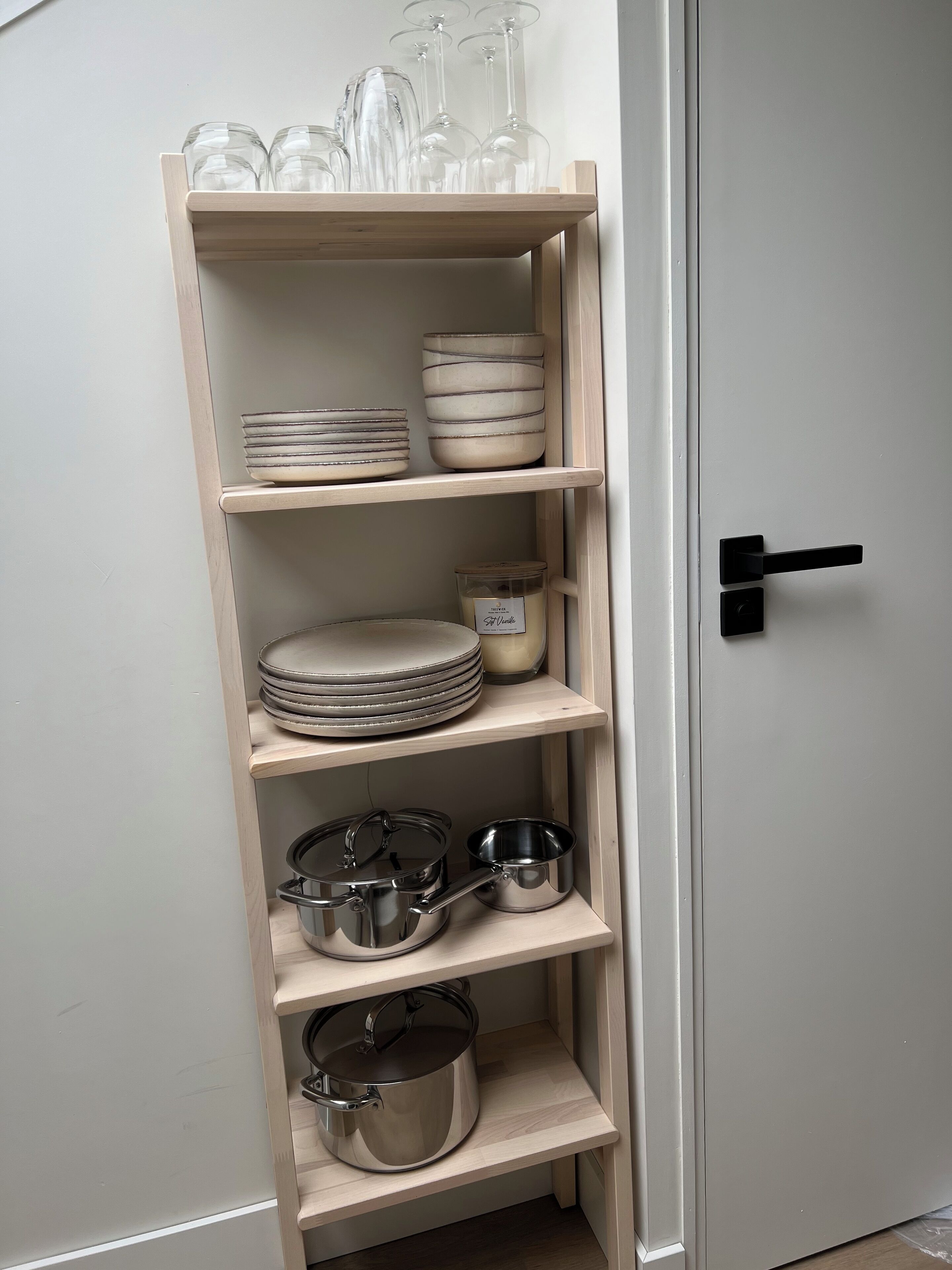 Uma cozinha com prateleiras de madeira que exibem pratos, tigelas e utensílios de cozinha.