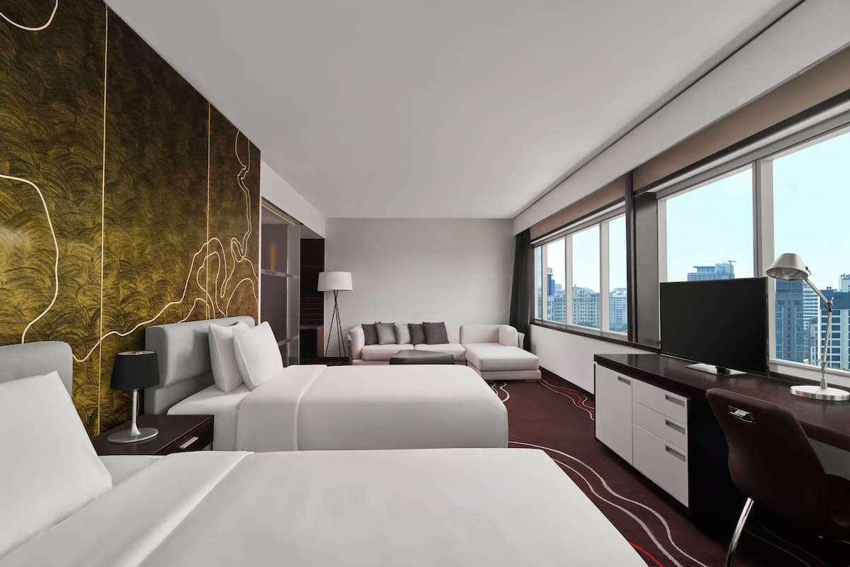 Quarto de hotel moderno com uma cama grande, um sofá, uma escrivaninha e uma televisão.