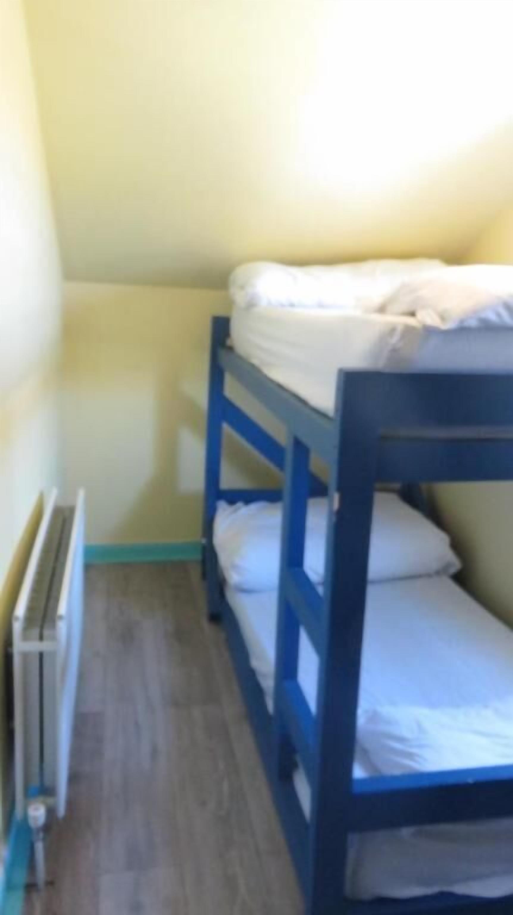 Quarto com beliche, radiador e piso de madeira.