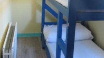 Quarto com beliche, radiador e piso de madeira.