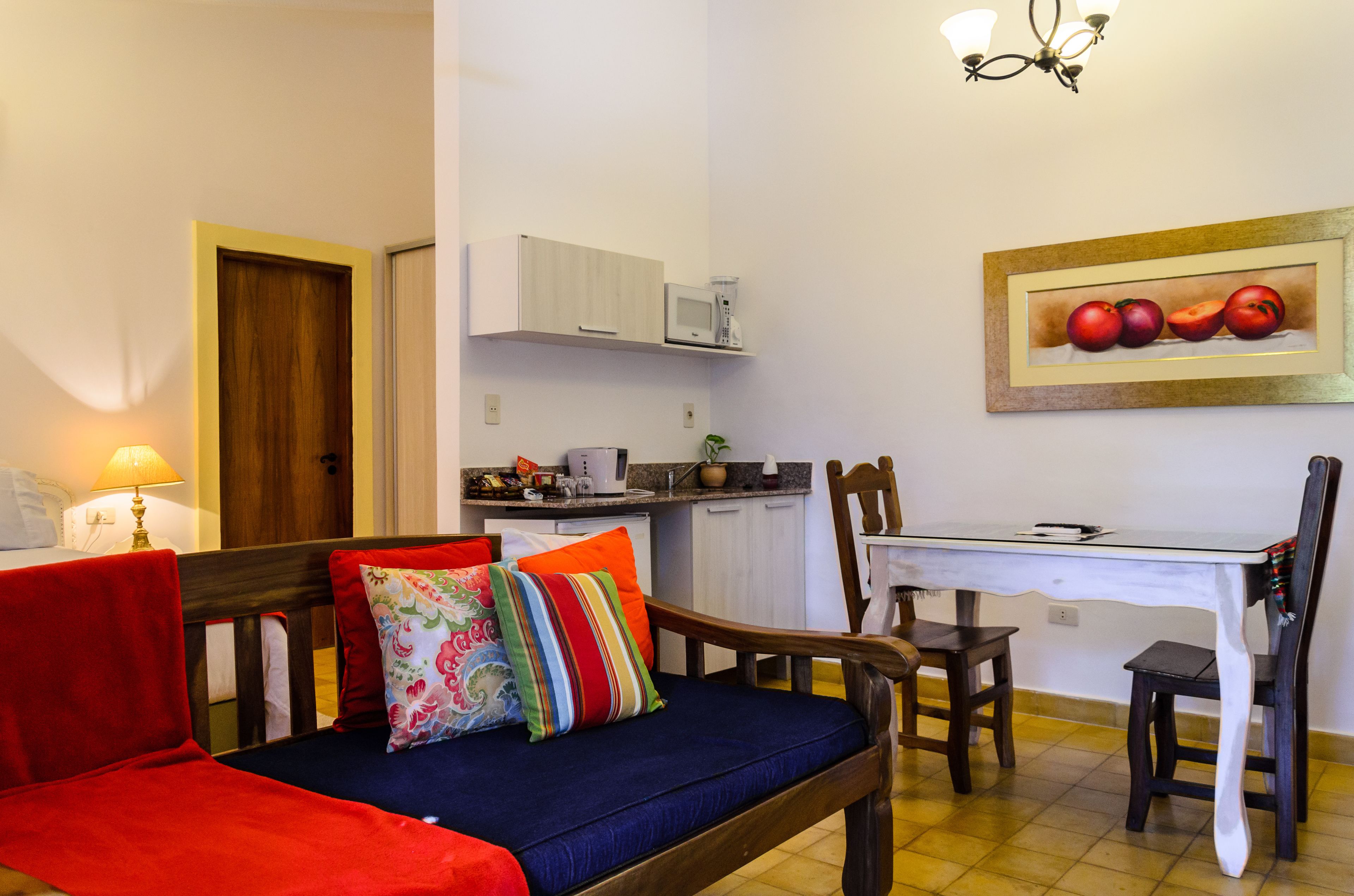 Uma sala de estar acolhedora com sofá, mesa de jantar e cozinha ao fundo.