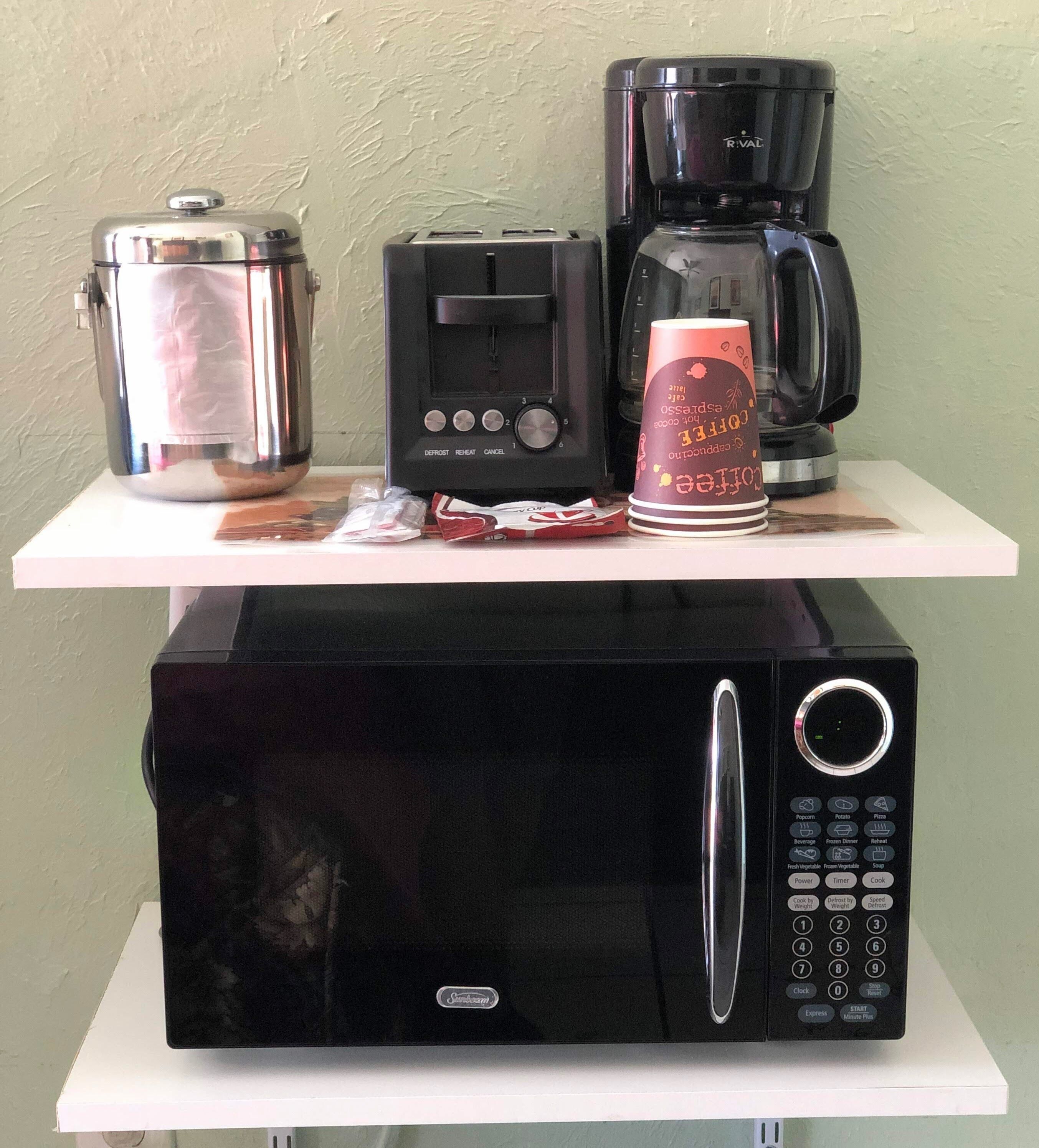 Uma bancada de cozinha com cafeteira, torradeira e micro-ondas.