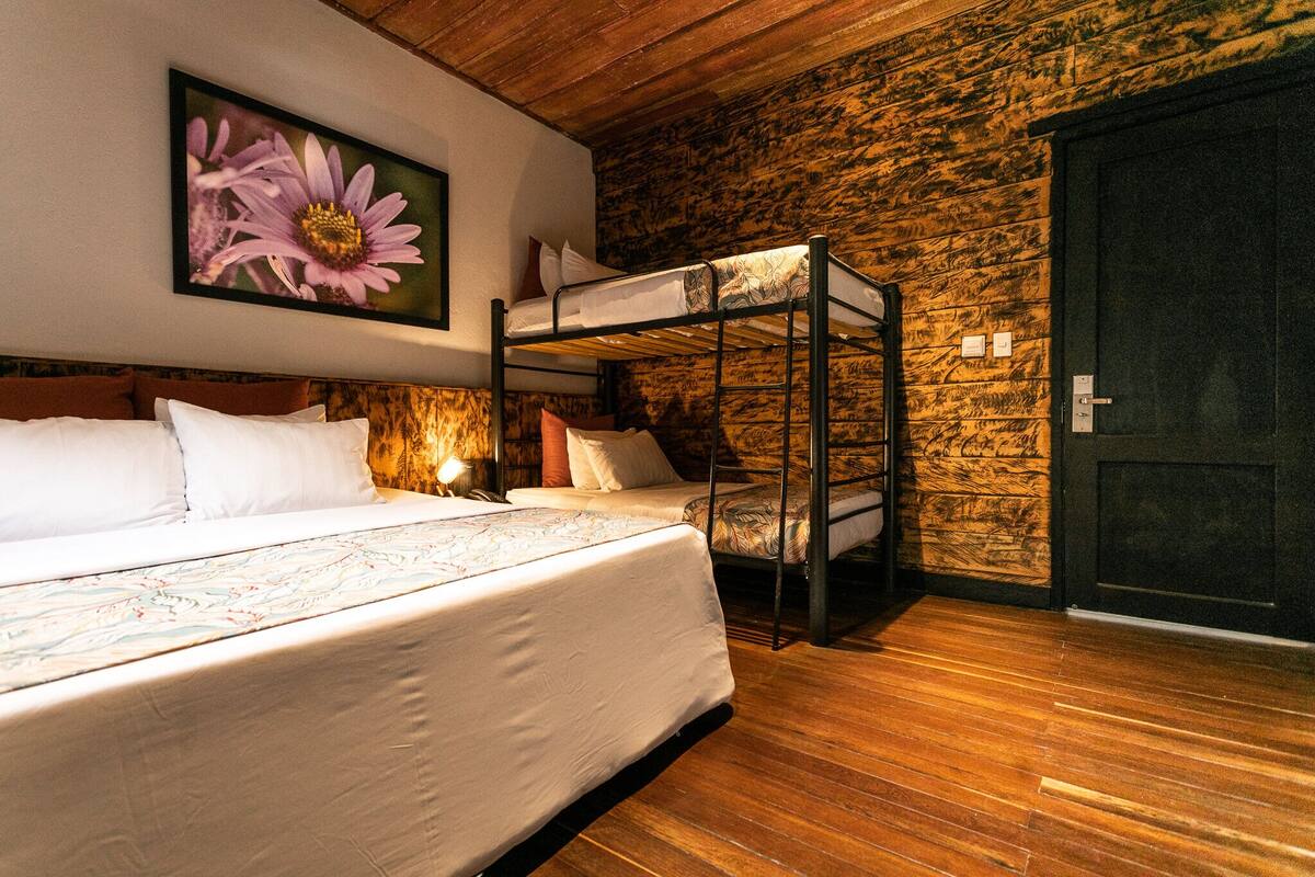 Quarto com uma cama de solteiro, uma grande pintura de uma flor, paredes de madeira e piso de madeira.