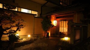 Um edifício tradicional japonês com um caminho de pedra que leva a uma entrada de madeira.