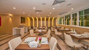 Um restaurante com várias mesas e cadeiras, uma grande janela com vista e um design moderno no teto.