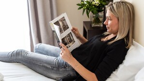 Uma pessoa deitada na cama lendo uma revista.