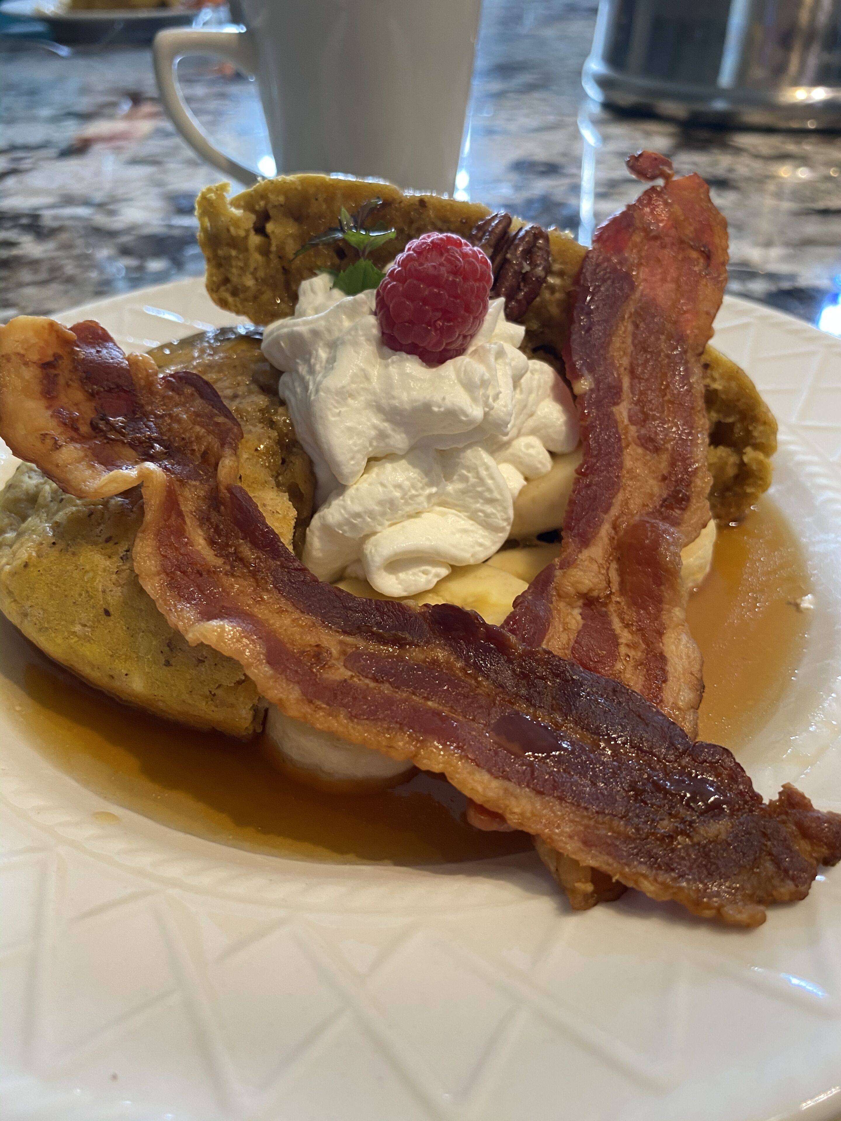 Prato de comida com bacon, chantilly e uma framboesa por cima.