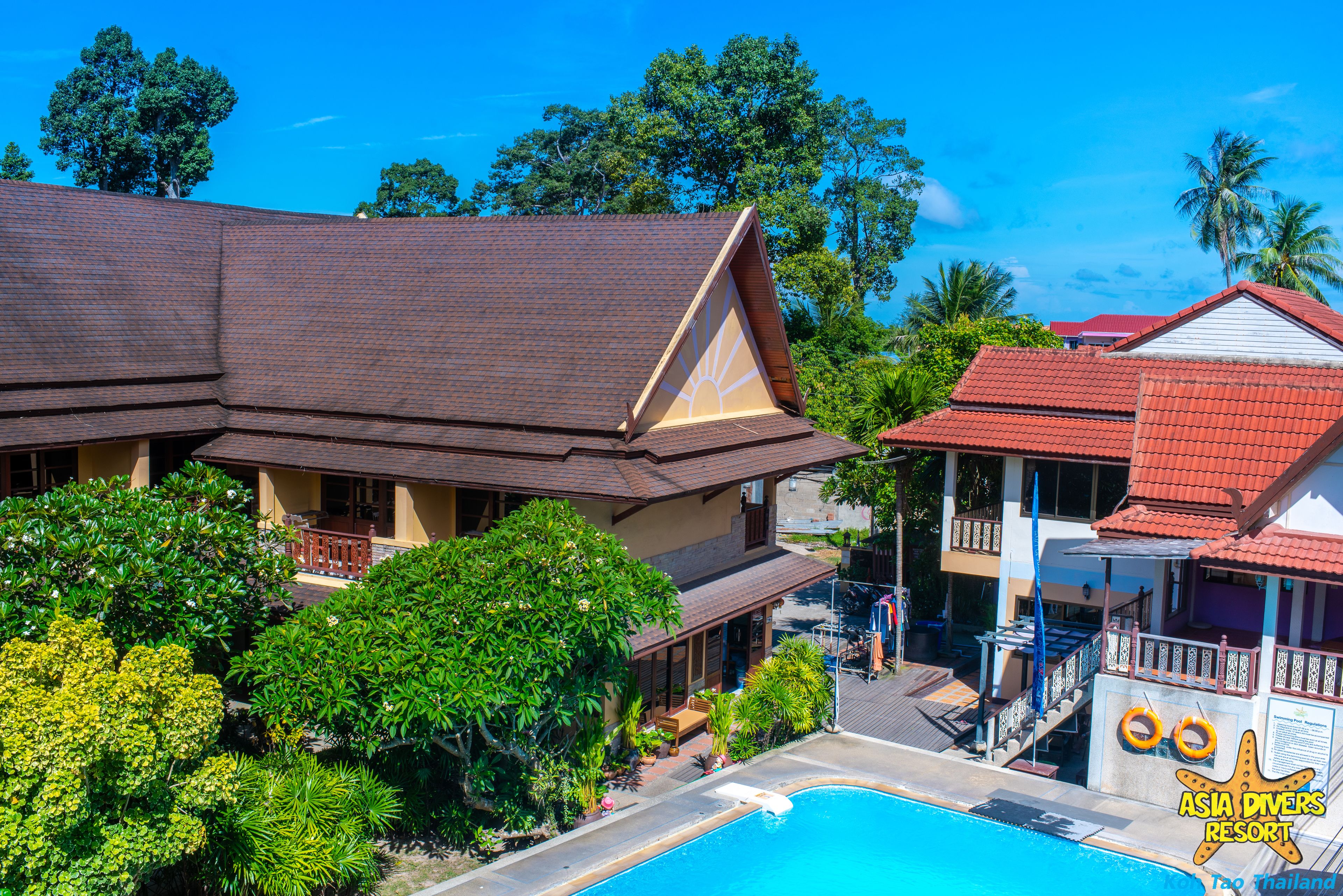 Resort com piscina, vários edifícios e vegetação exuberante.