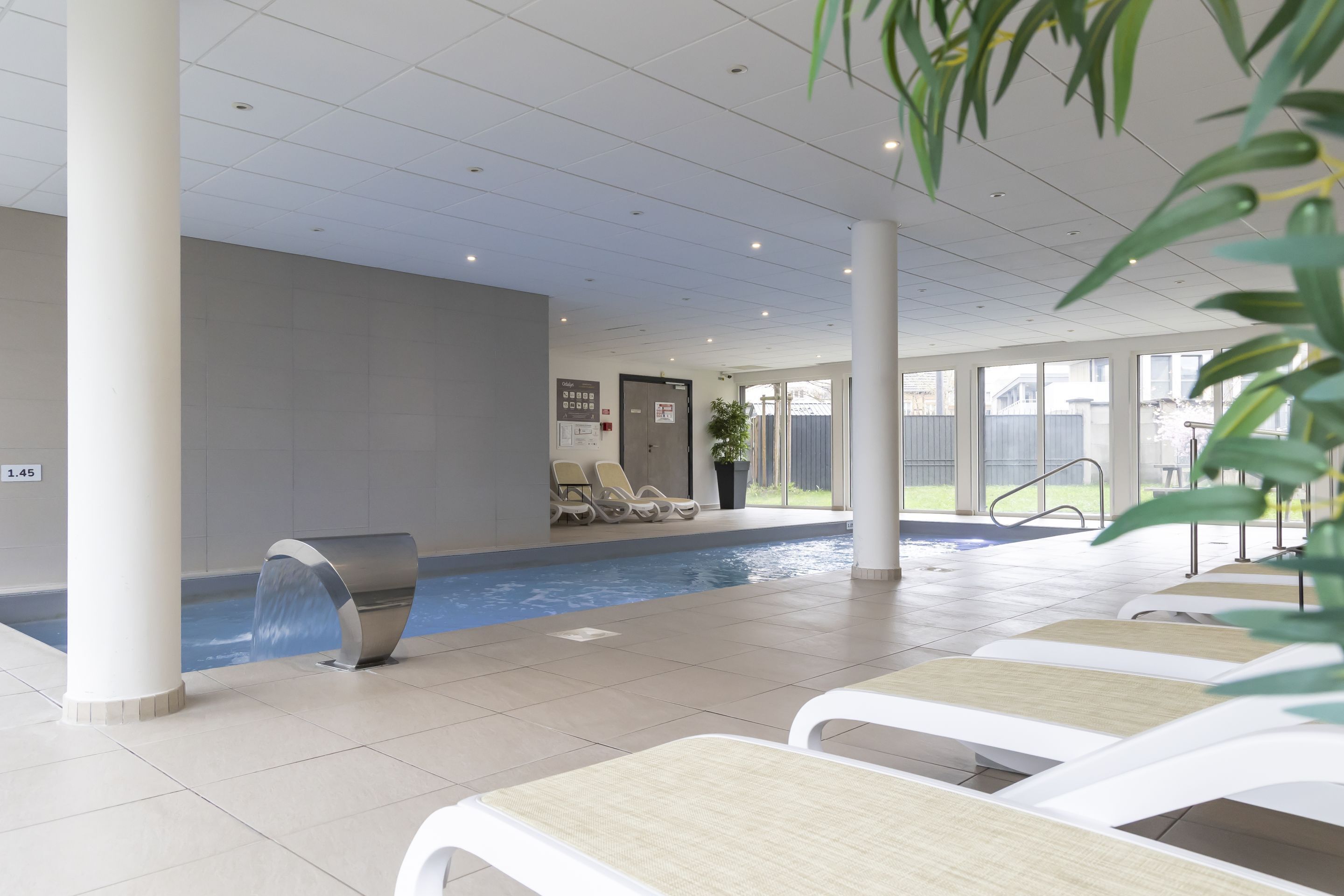 Uma área de piscina com espreguiçadeiras, um elemento aquático e vista para o exterior.