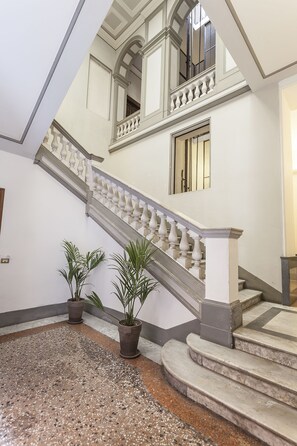 Uma escadaria imponente com balaústres brancos e piso de mármore que leva a um andar superior.