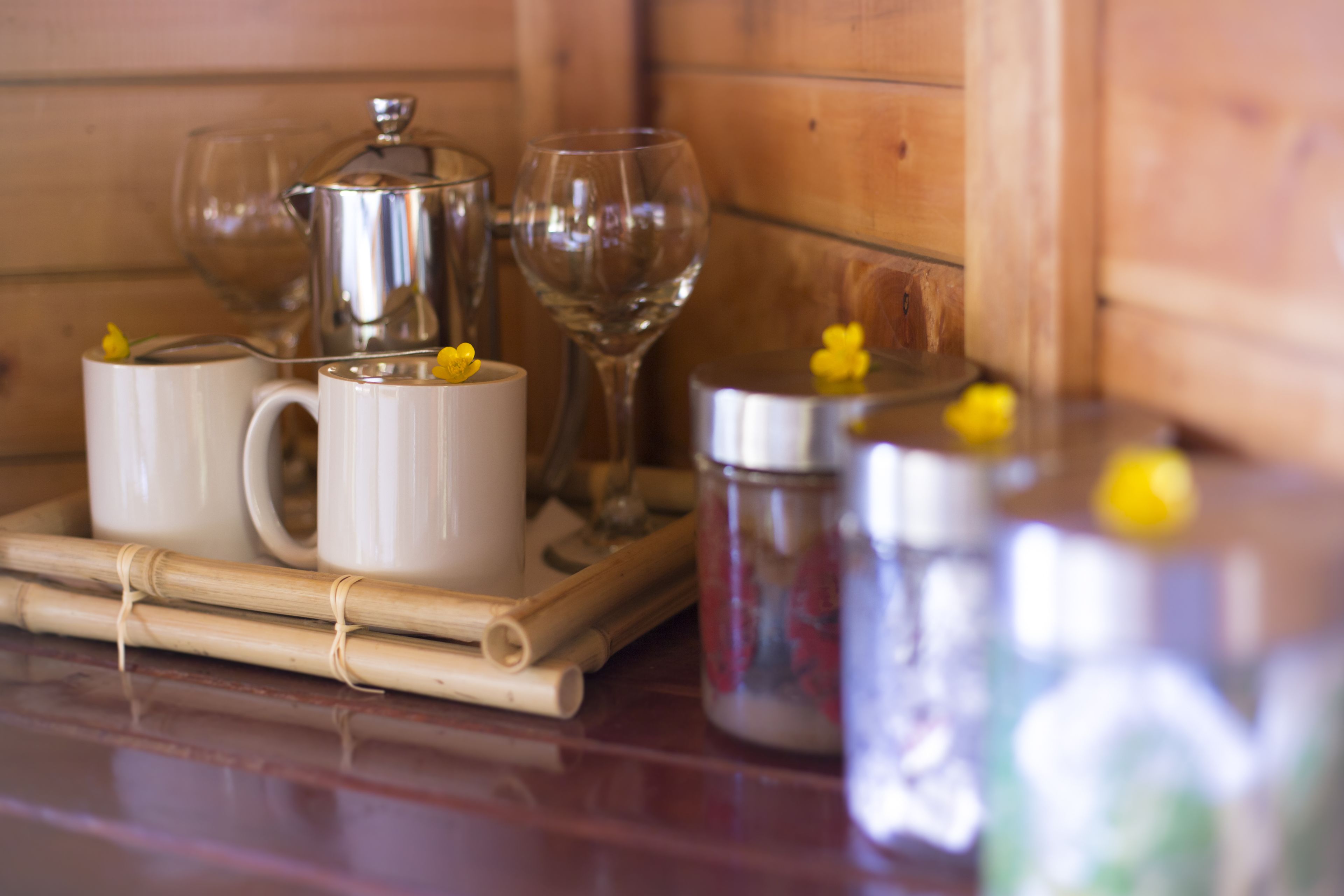 Interior em madeira com uma mesa posta para chá, incluindo um bule, xícaras e um copo.