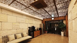 Um lobby moderno com parede de pedra, sofá, balcão de recepção e luminária decorativa no teto.