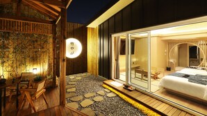 Quarto de hotel moderno com uma cama grande, porta de vidro deslizante para uma varanda e fachada de madeira.