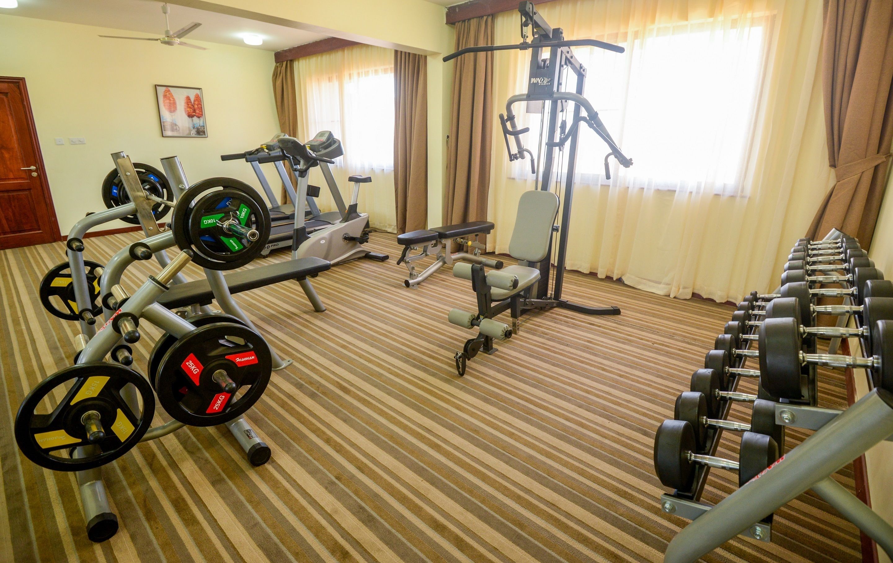 Uma academia com diversos equipamentos de exercício, incluindo esteiras, aparelhos de musculação e pesos livres.